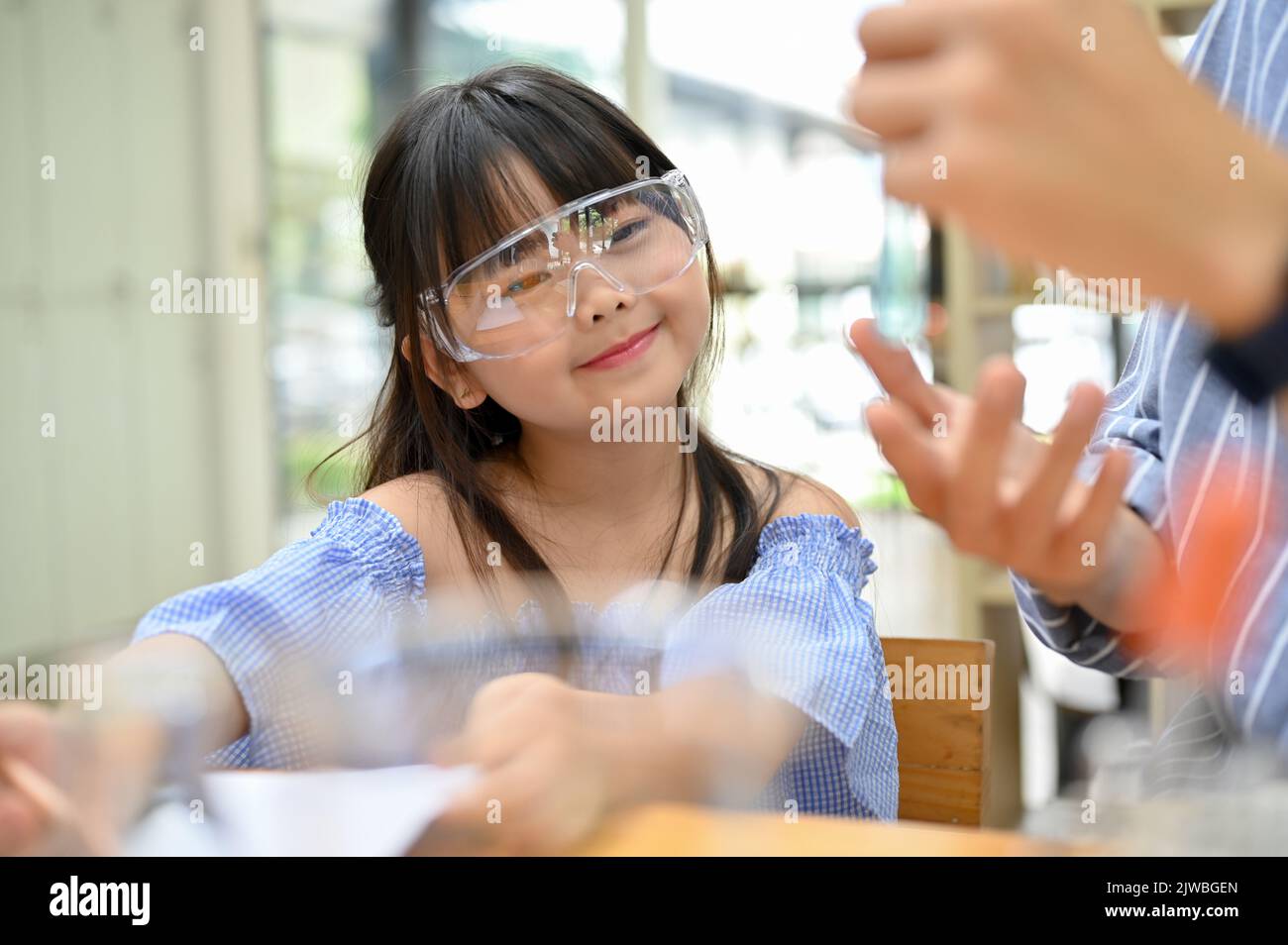 Cute and charming Asian girl with experiment goggles enjoys learning ...