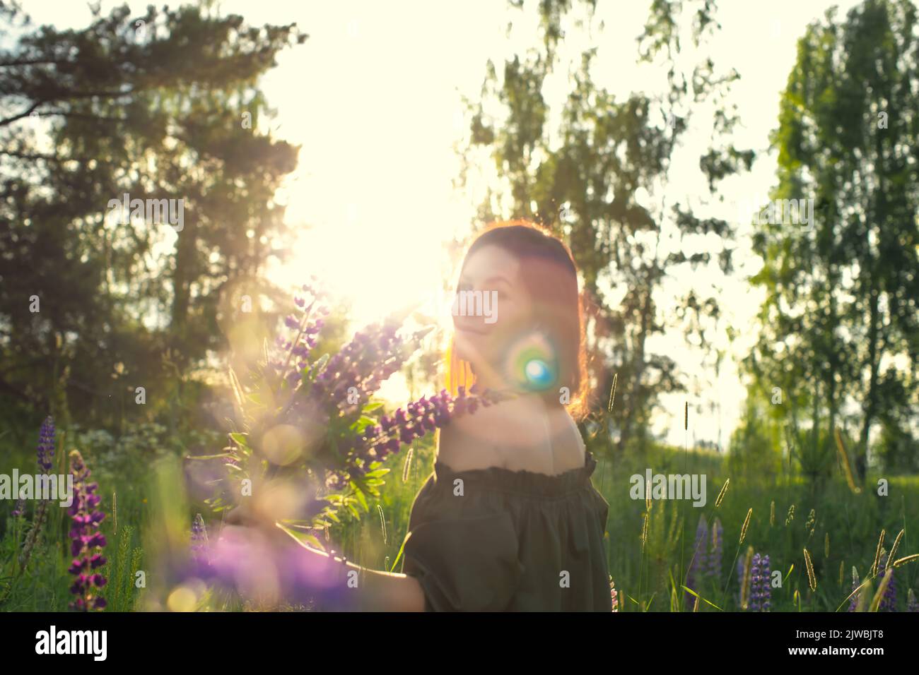 An attractive woman in a field with a summer bouquet of wildflowers ...