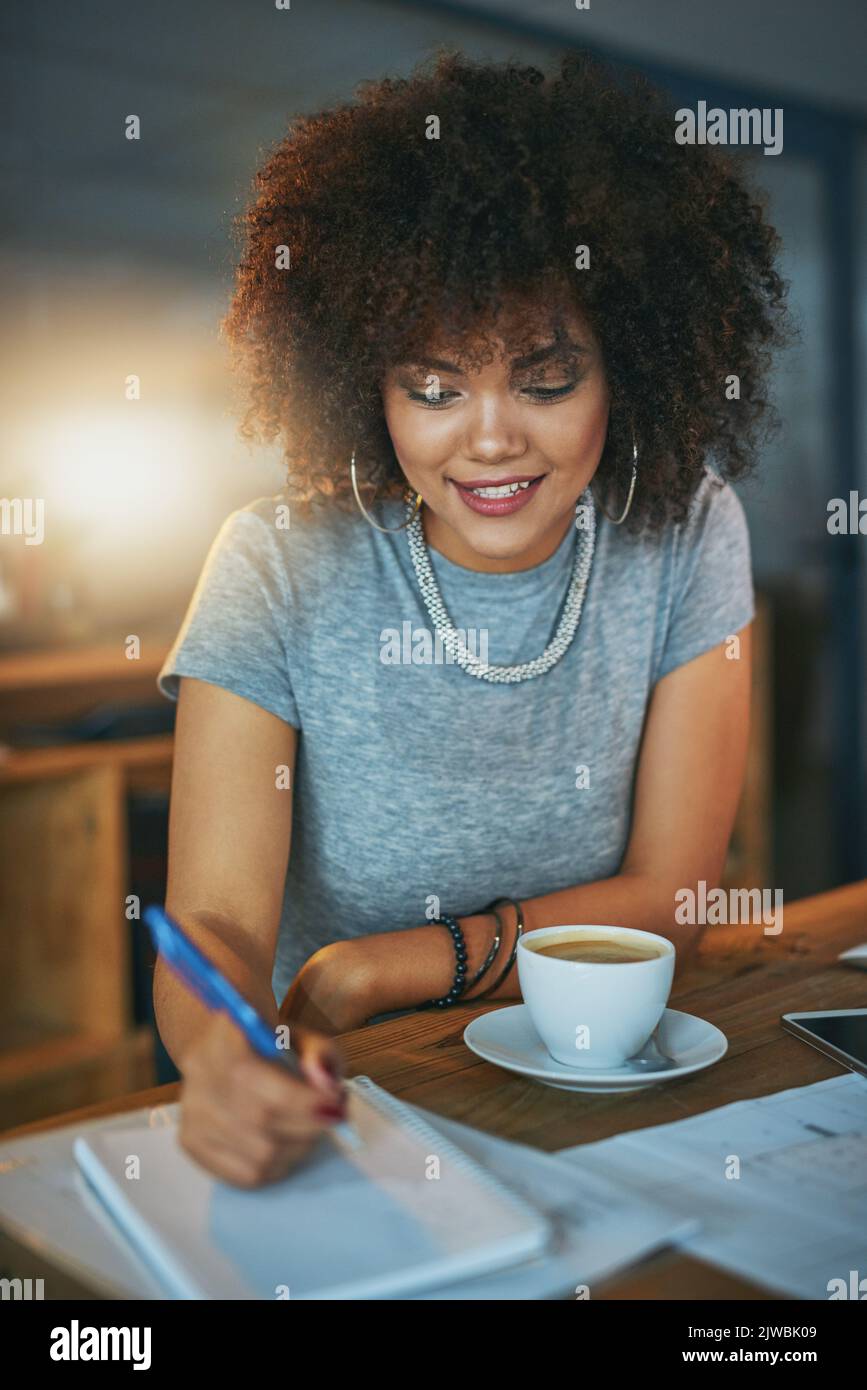Setting tasks for tomorrows work day. a young woman writing in a ...