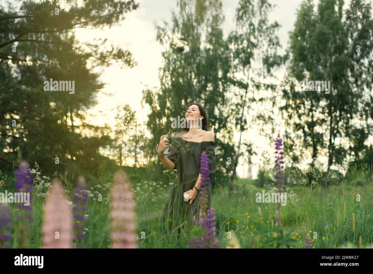 An attractive woman in a field with a summer bouquet of wildflowers ...