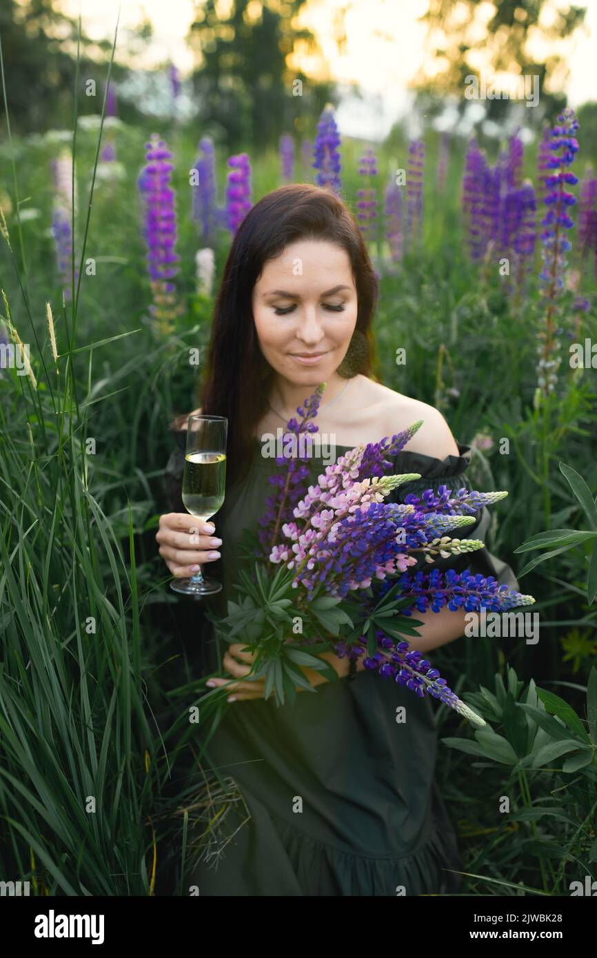 An attractive woman in a summer field with a glass of champagne and a ...