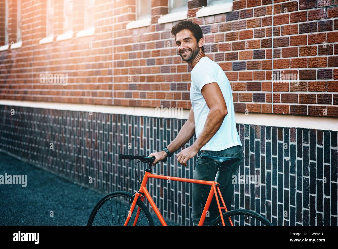 Nothing beats a bike ride around town. a handsome young man walking ...