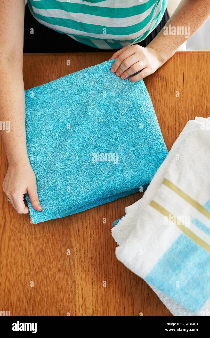 Folding up some linen. a person folding a towel on a table Stock Photo ...