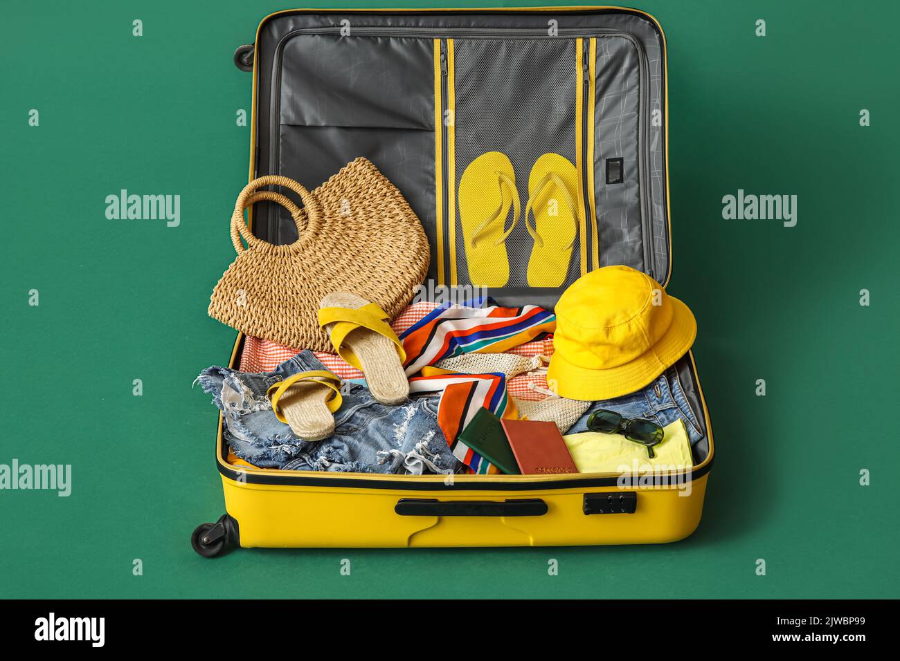 Suitcase with clothes, beach accessories and documents on green ...