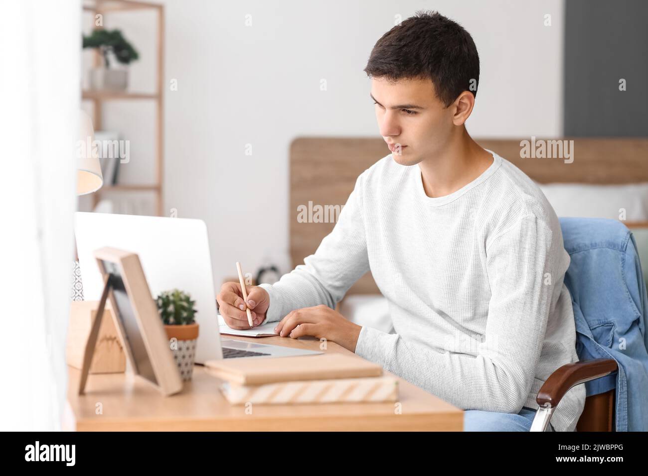 Teenage boy studying with laptop at table in bedroom Stock Photo - Alamy