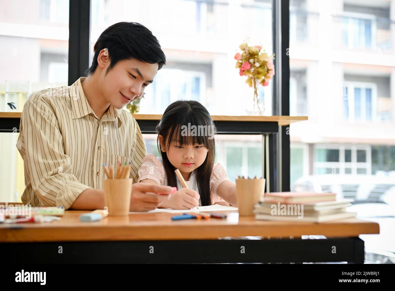 A lovely young Asian girl concentrates on learning art in the art ...