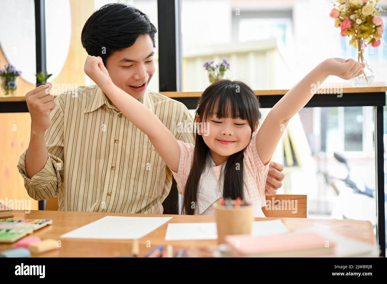 Happy and cheerful young Asian girl raises her hands after finished ...