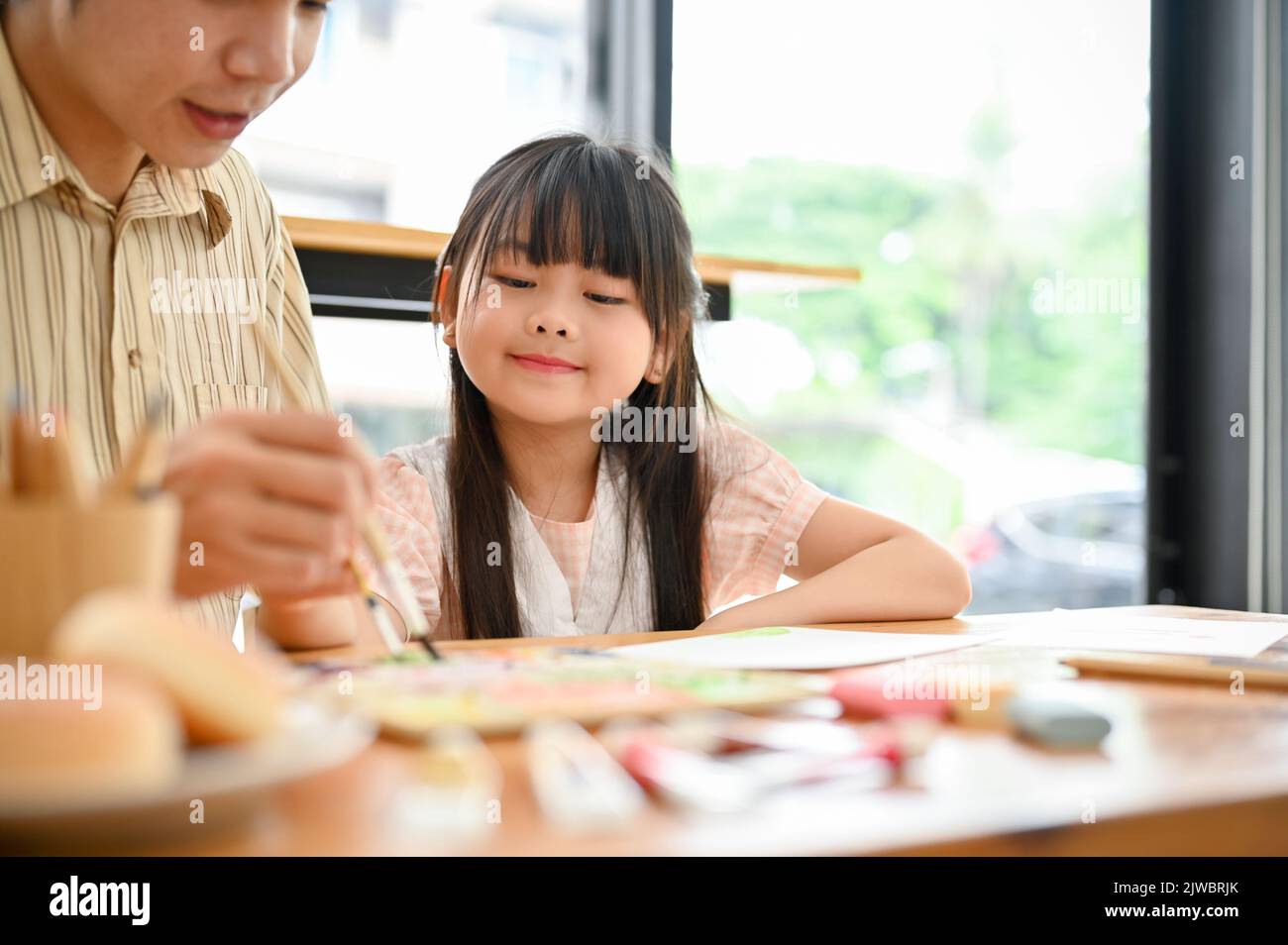 Attractive young Asian kid drawing and painting a watercolor with her ...