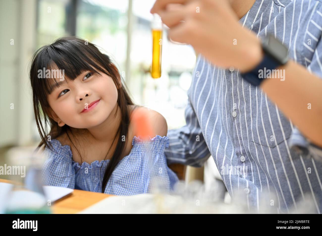 A pretty young Asian girl studying science, learning how to do a ...