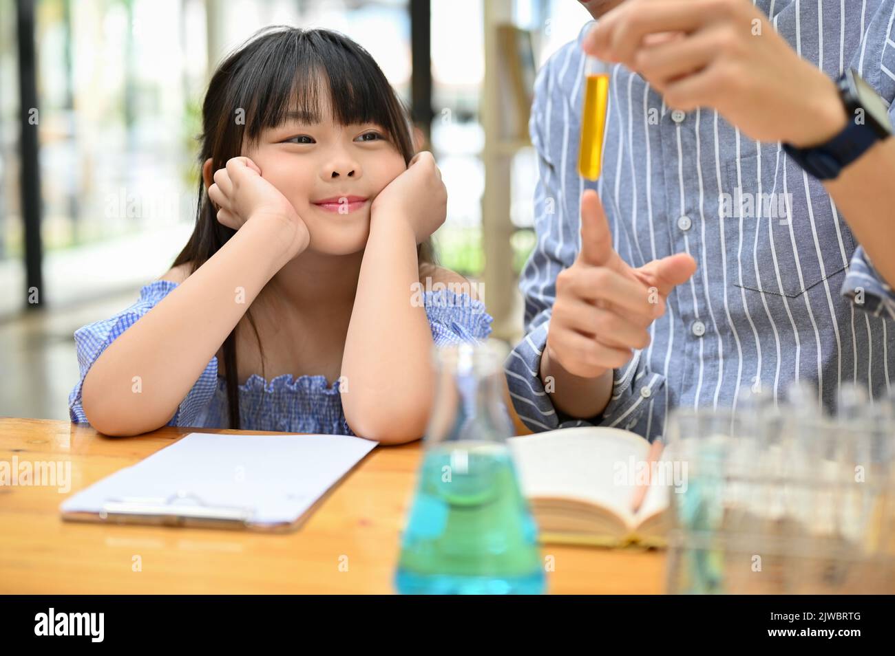 The pretty young Asian girl enjoys learning science, looking at her ...