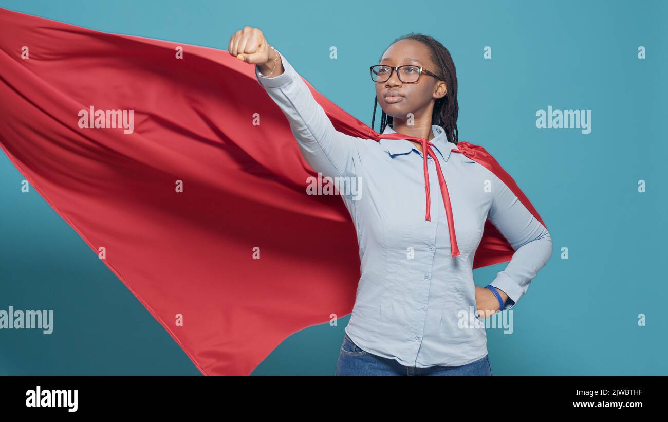 Portrait of superhero with flying red cape on camera, posing as action ...
