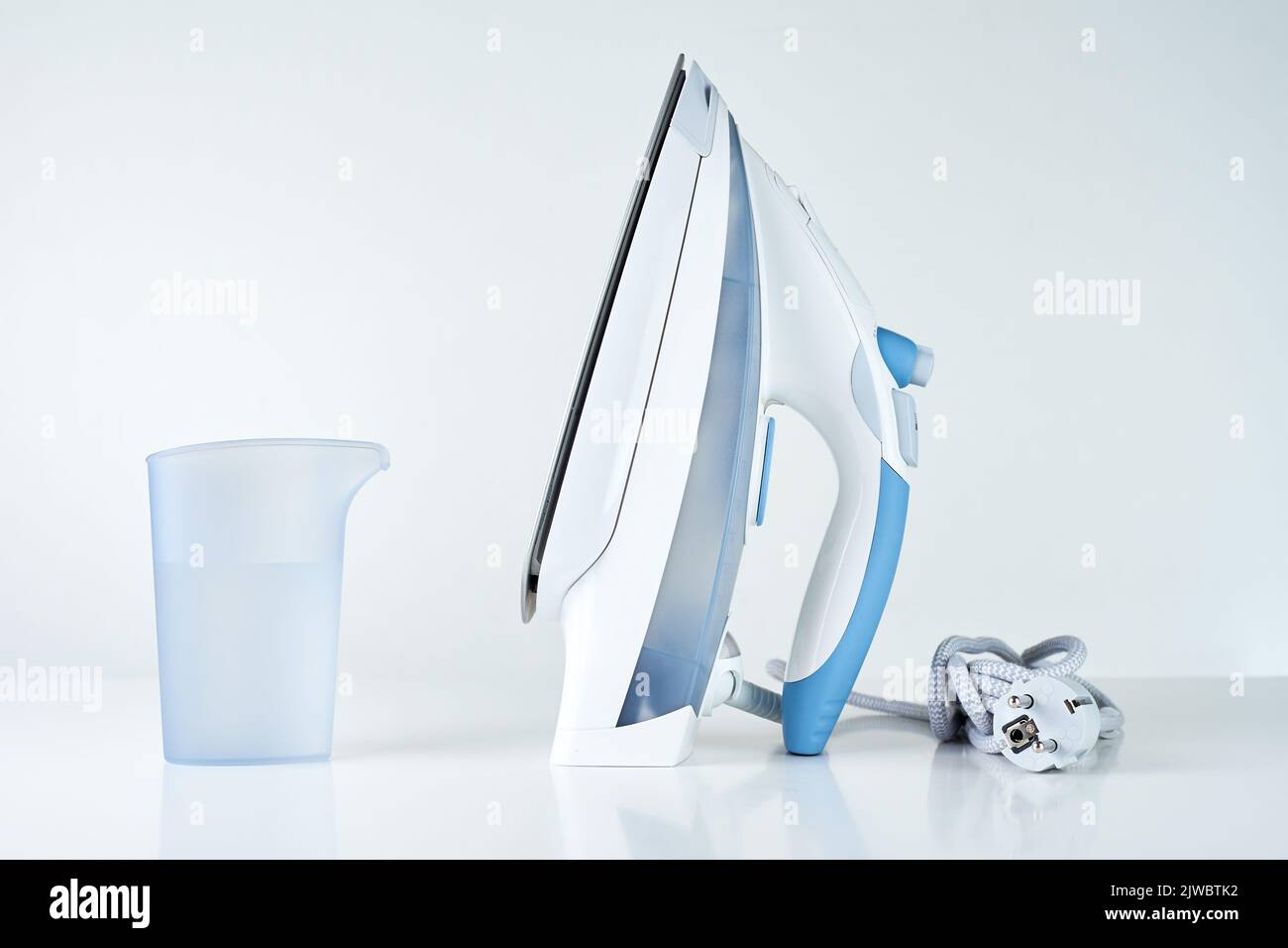 New iron with electrical cable and water for steam on white background ...
