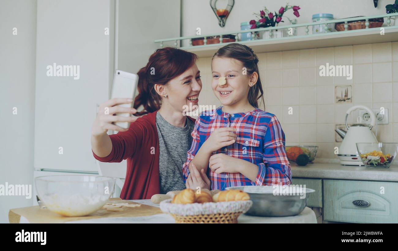 Smiling mother together with funny cute daughter taking selfie photo ...