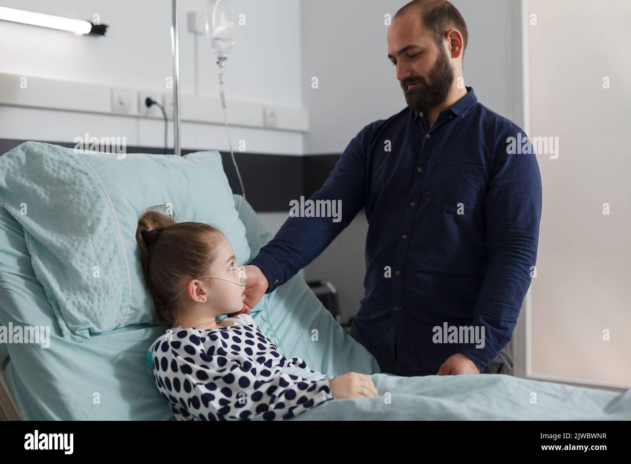 Caring parent taking care of ill little girl while touching her face ...