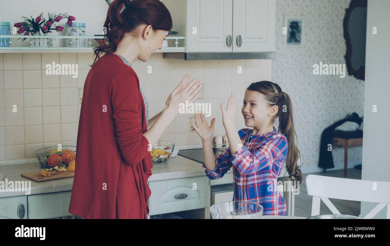 Happy young mother and cute funny daughter playing clapping hands game and have fun while ...