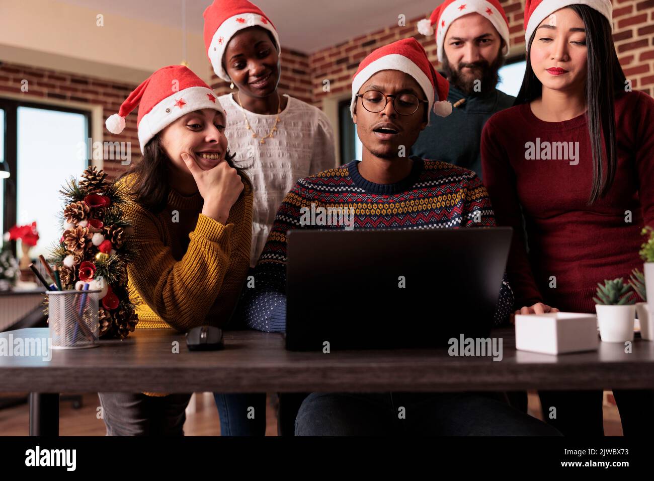 Festive diverse colleagues brainstorming ideas at work, wearing santa ...