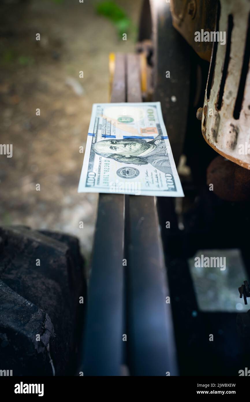 A hundred dollar bill lies on the engine drive belts of a rural walk ...