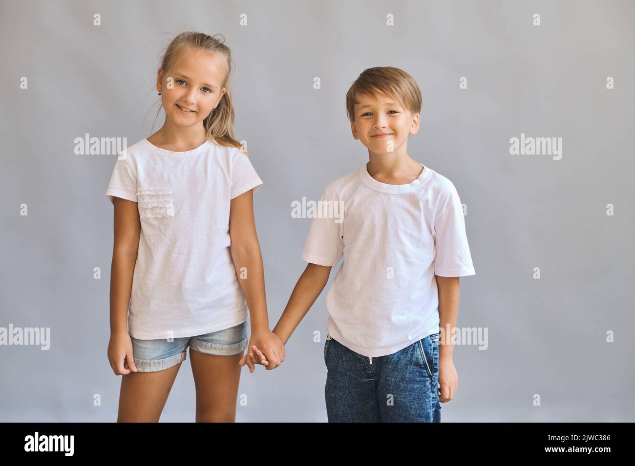 Cute two kids, little boy and girl in white t-shirts on gray background ...