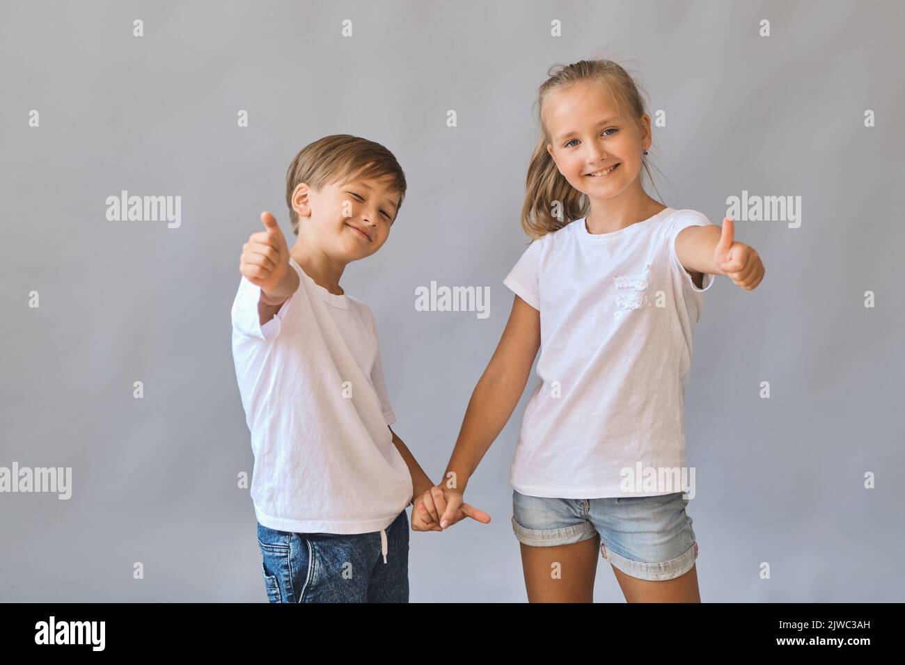 Cute two kids, little boy and girl in white t-shirts on gray background ...