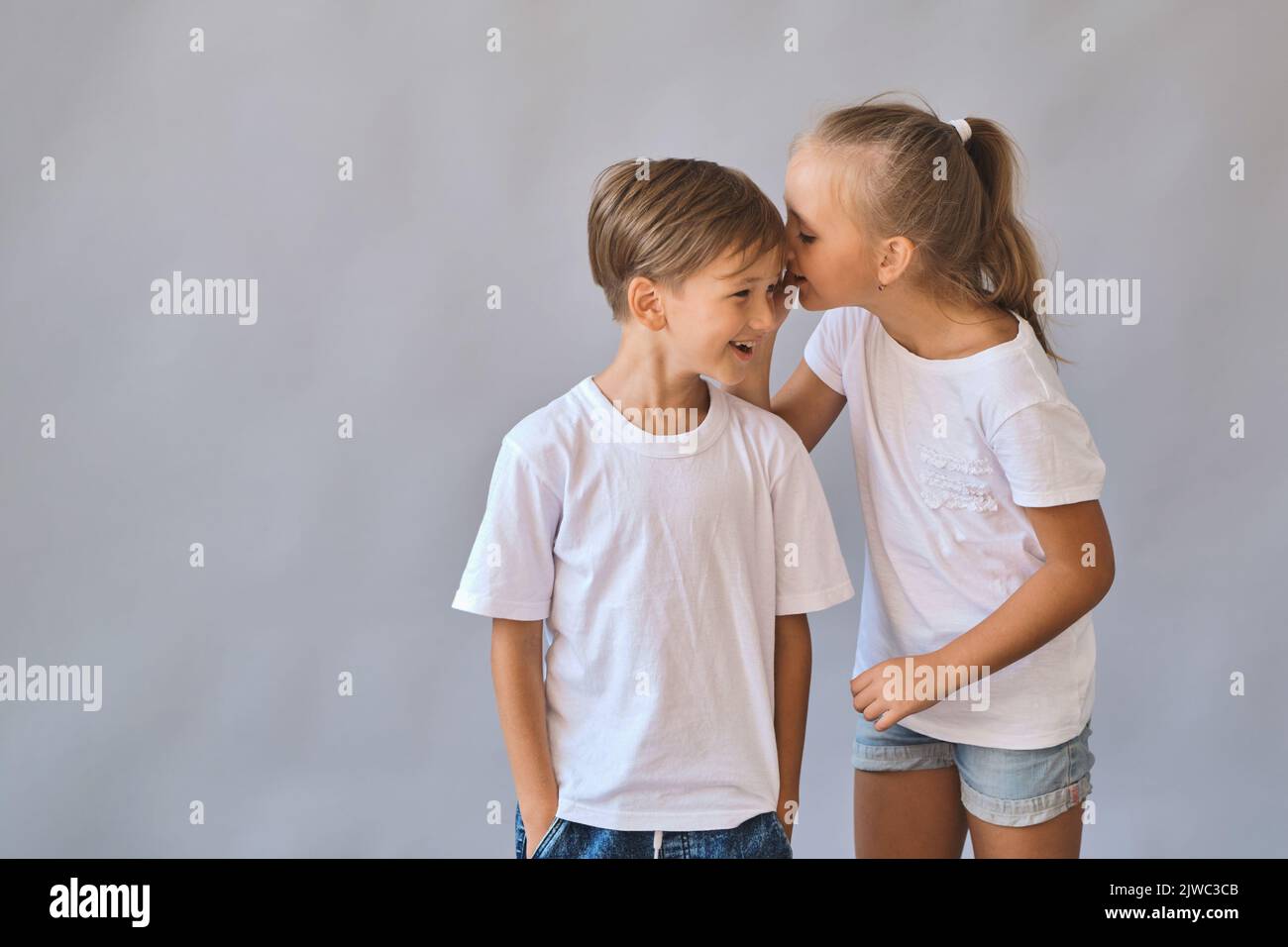 Cute two kids, little boy and girl in white t-shirts on gray background ...
