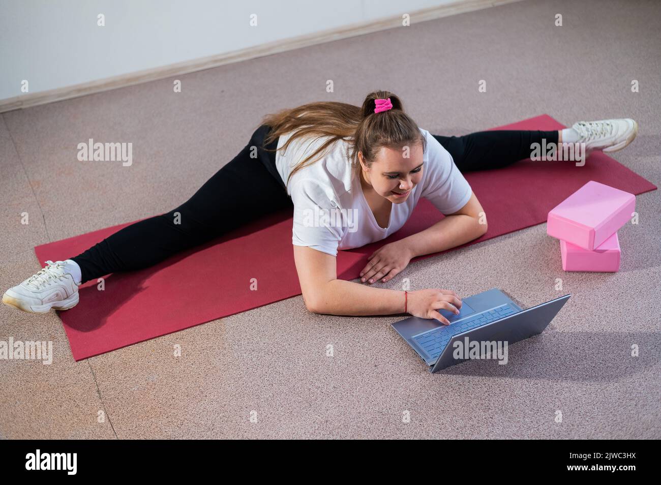 Young caucasian fat woman doing bends on a sports mat and watching a ...