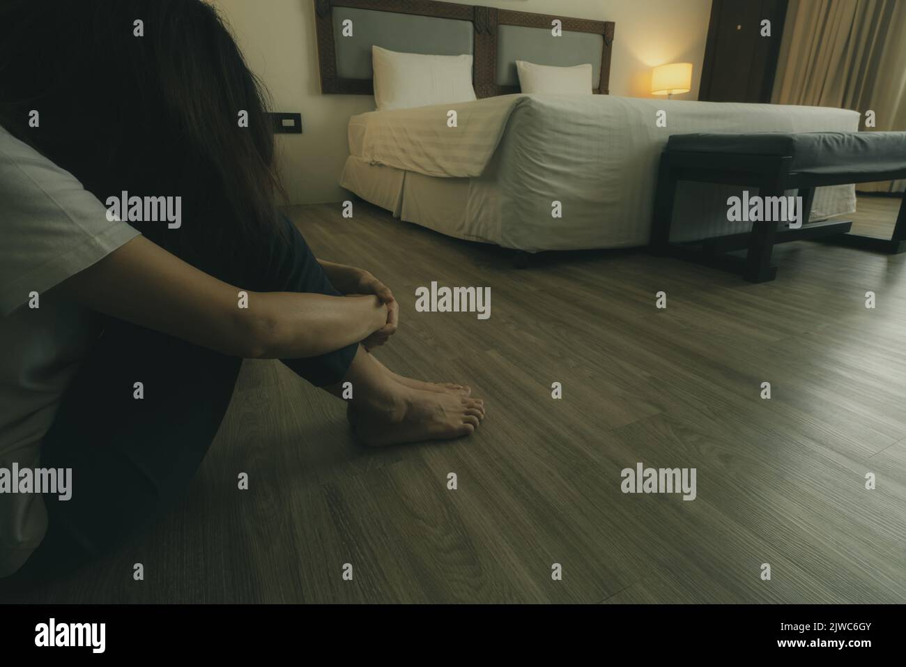 Depressed and stressed woman sitting on vinyl tiles floor near bed in ...
