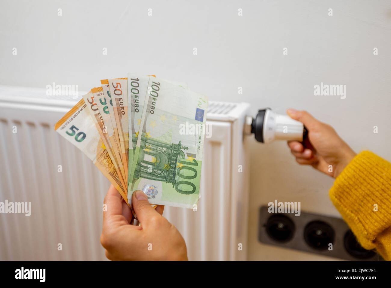 Person holding euro banknotes near heater at home Stock Photo - Alamy