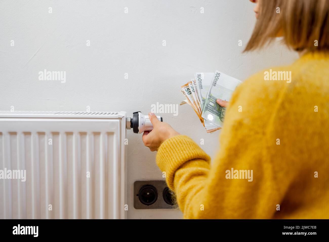 Person holding euro banknotes near heater Stock Photo - Alamy