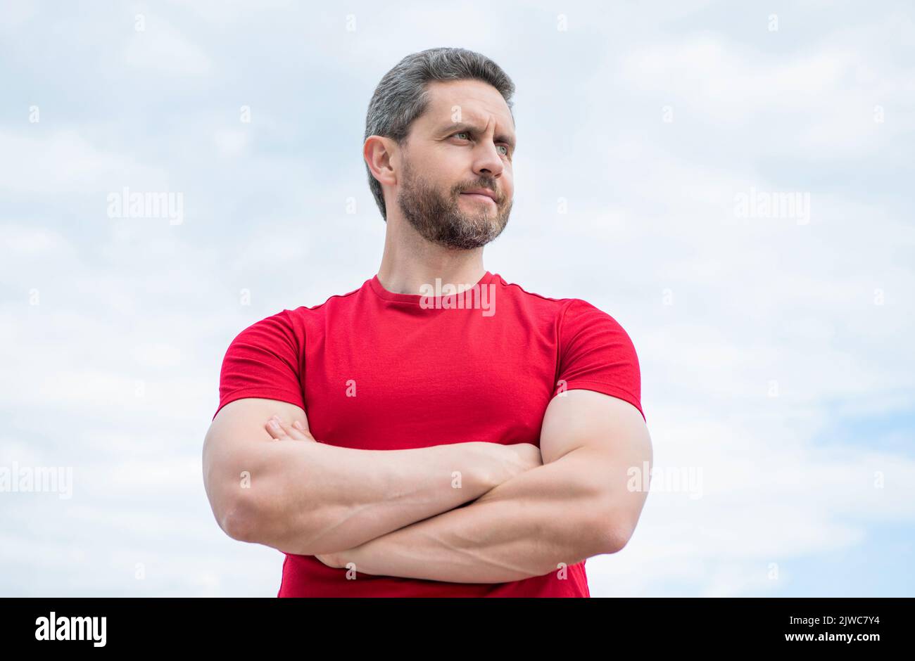 confident guy in red shirt crossed hands on sky background Stock Photo - Alamy