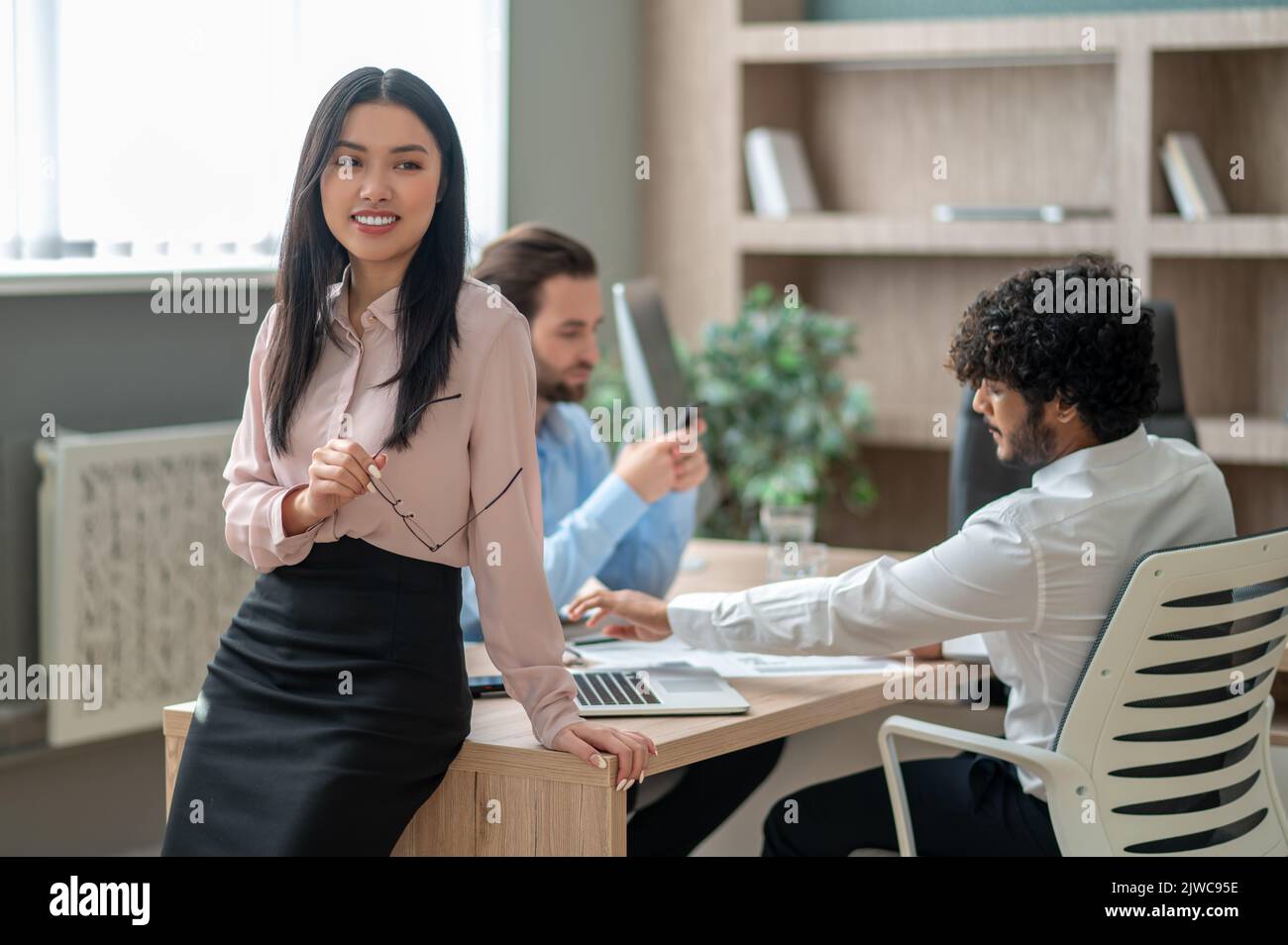 Good-looking asian young girl working with colleagues in the office ...