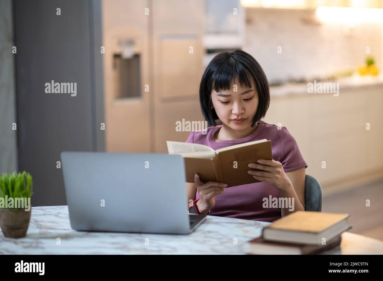 Pretty young asian girl reading a book and looking involved Stock Photo ...