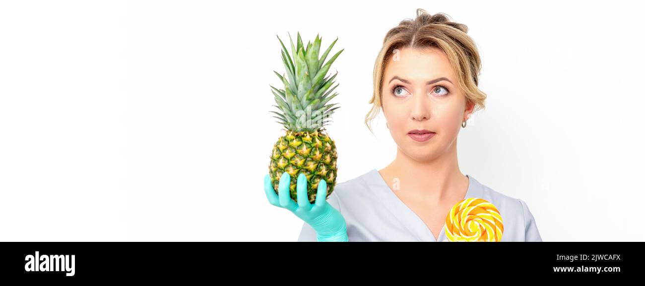 Young caucasian female doctor nutritionist holding fresh pineapple with ...