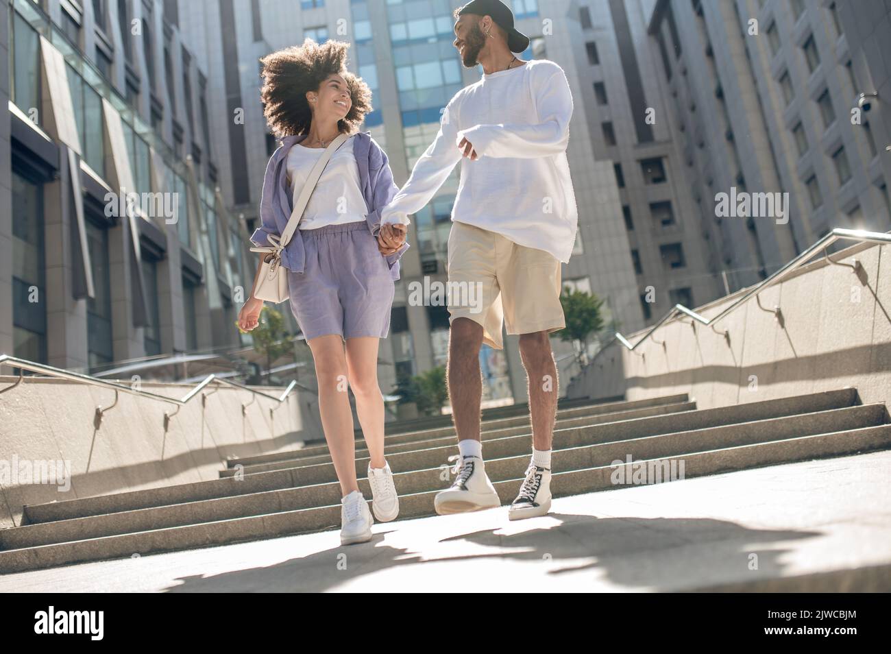 Cute couple walking hand in hand and looking happy Stock Photo - Alamy