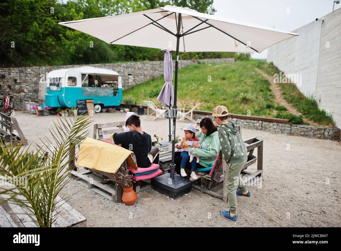 Family sit at cafe with cozy small mini bus food market Stock Photo - Alamy