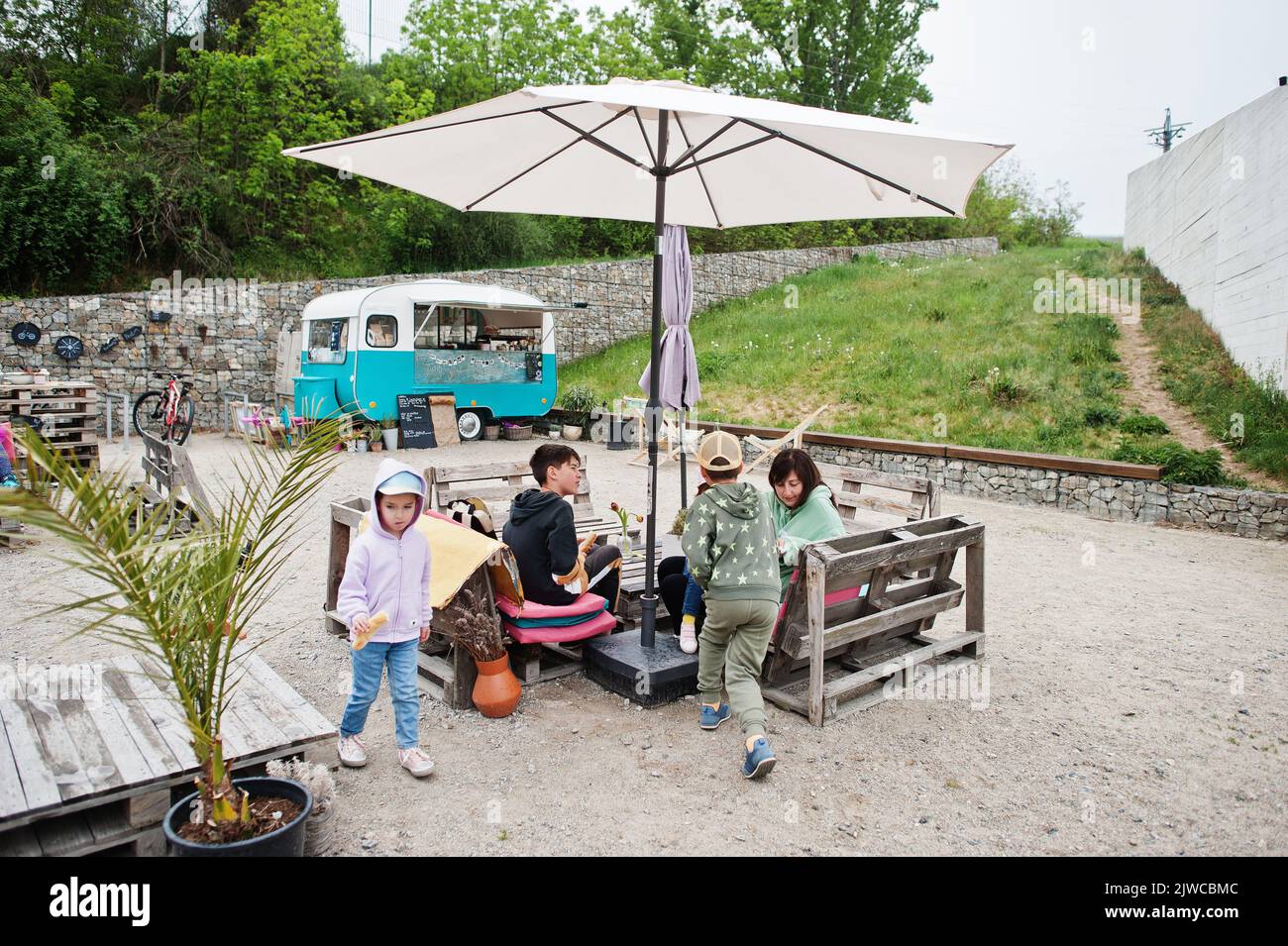 Family sit at cafe with cozy small mini bus food market Stock Photo - Alamy