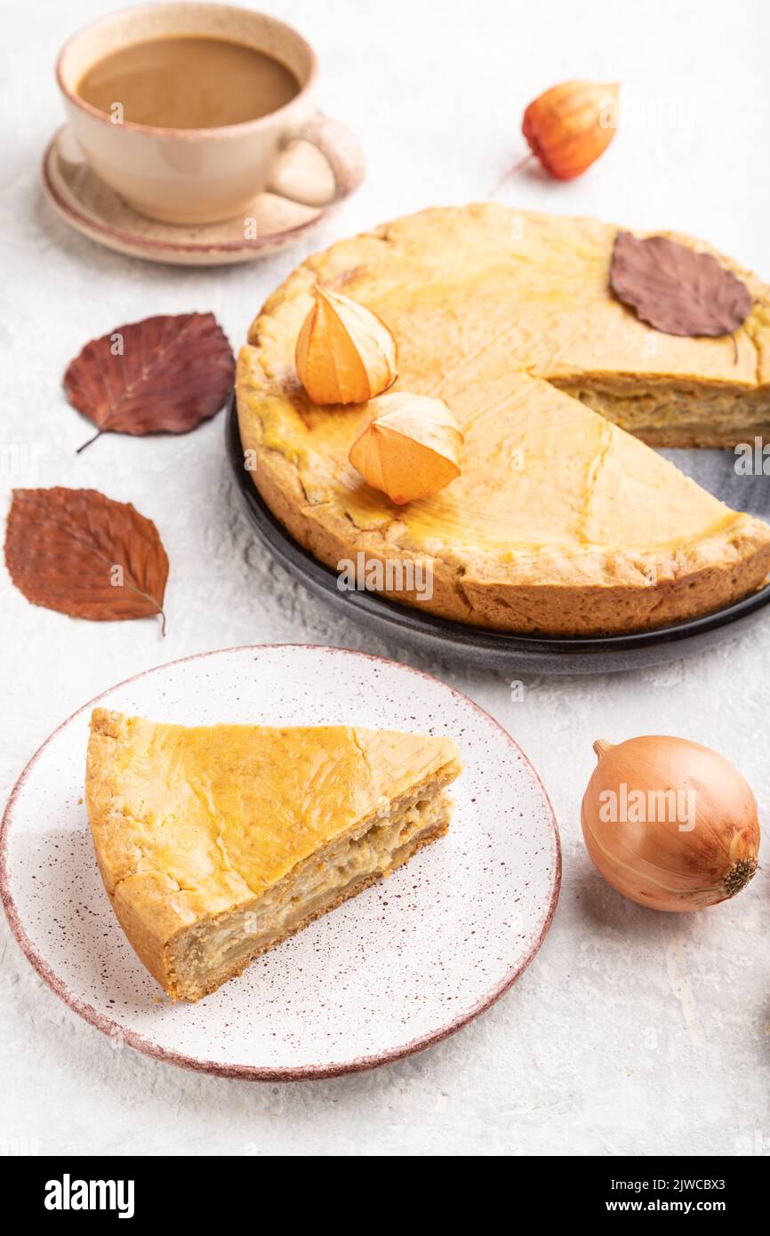 Autumn onion pie decorated with leaves and cup of coffee on gray ...