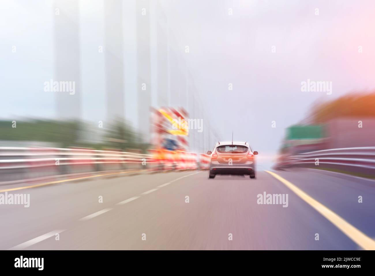 Freeway and a lone car driving next to attention signs and closed lane ...