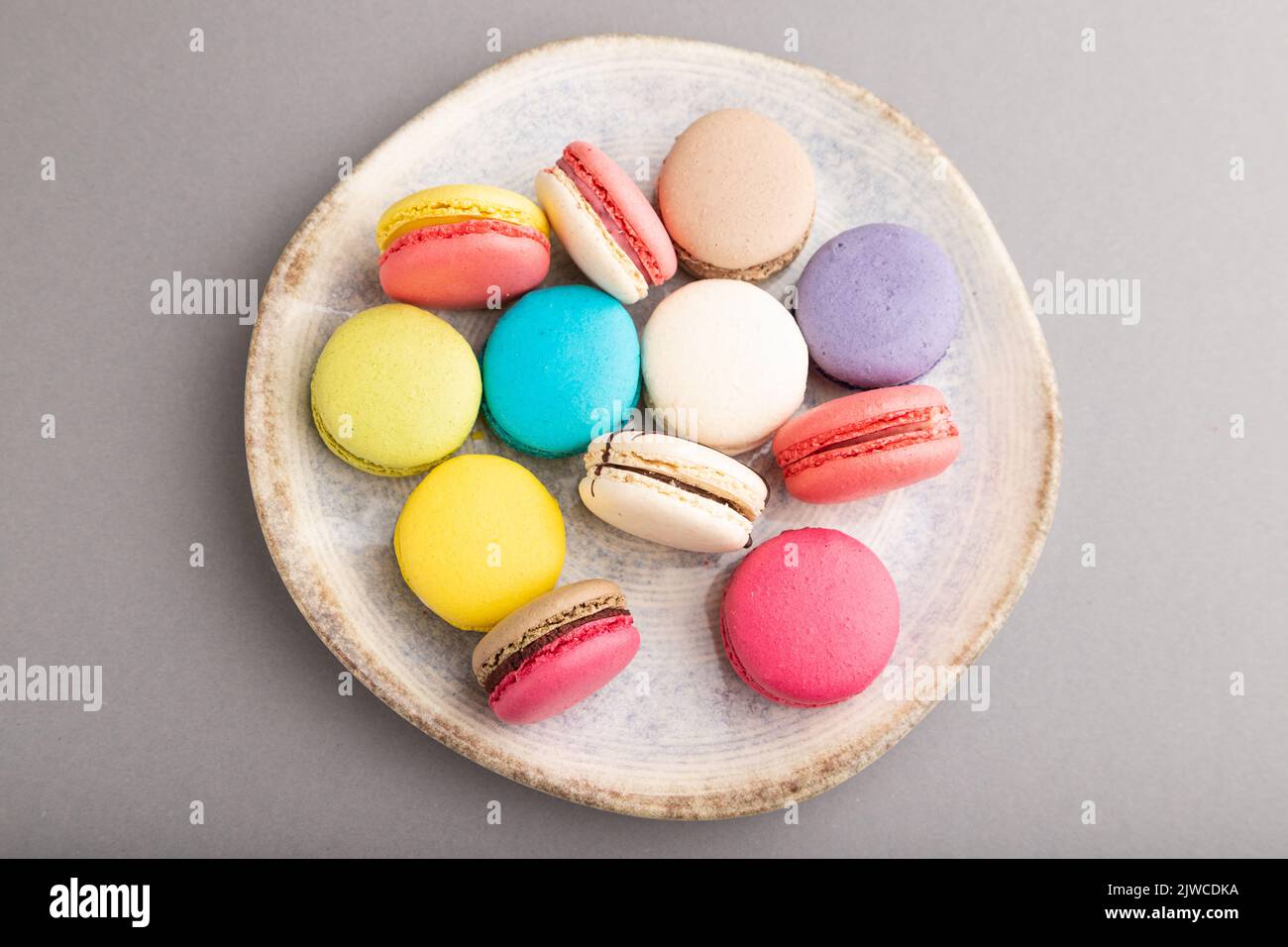 Multicolored macaroons on ceramic plate on gray pastel background. top ...