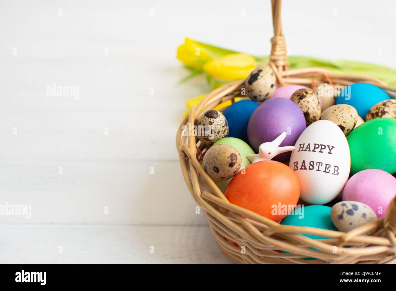 Wicker baskets with bright colorful eggs and with text Happy Easter and ...
