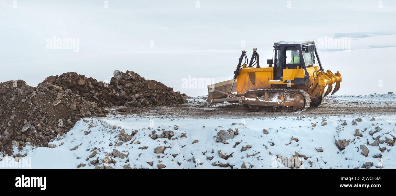 Bulldozer working on road construction site in grading phase in winter ...