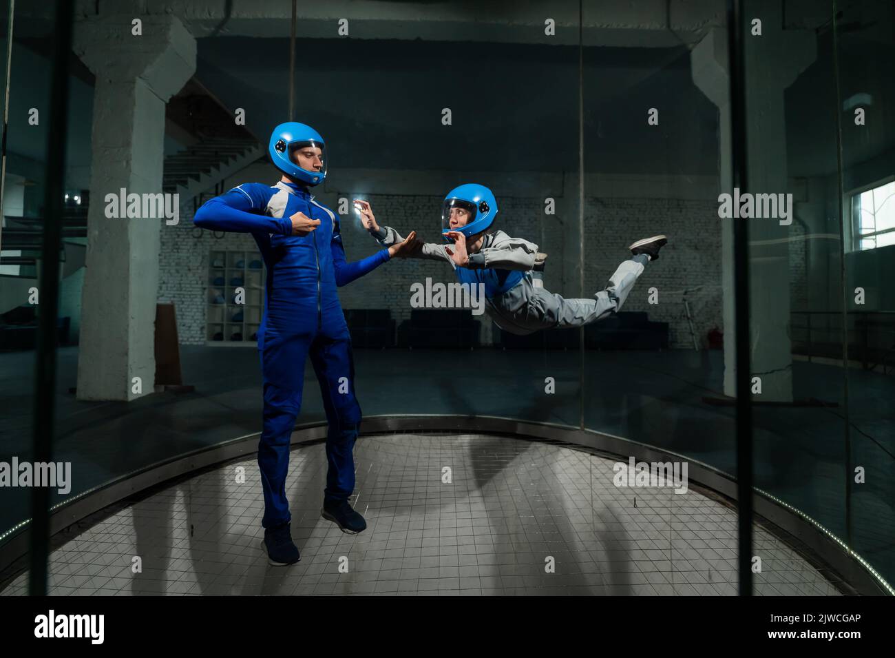 A man teaches a woman how to fly in a wind tunnel. Free fall simulator ...