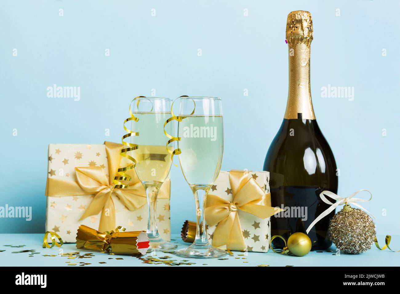 Champagne bottle with confetti, glasses and christmas decor on colored ...