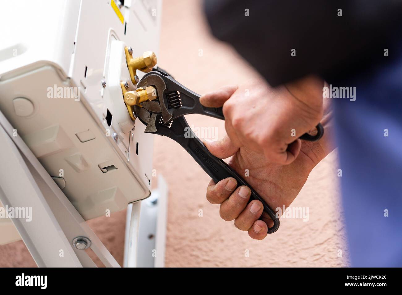 Close upof male worker's hands tightening wrench of air conditioner ...