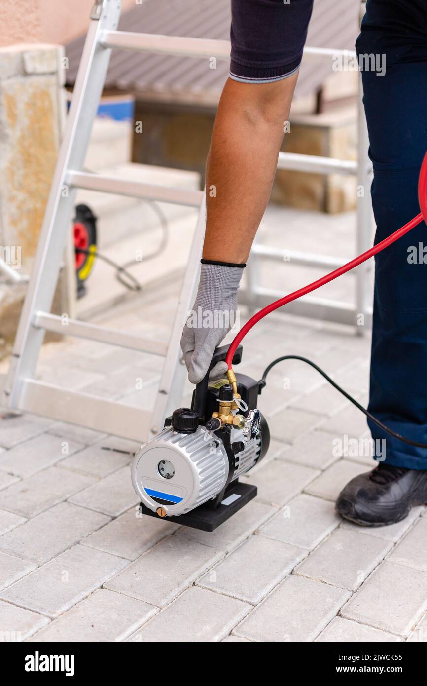 Close up of vacuum pump to pump air out of air conditioner. Male worker ...