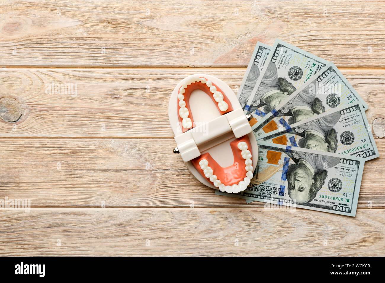 Closeup model of a human jaw with white teeth and dollar bill ...