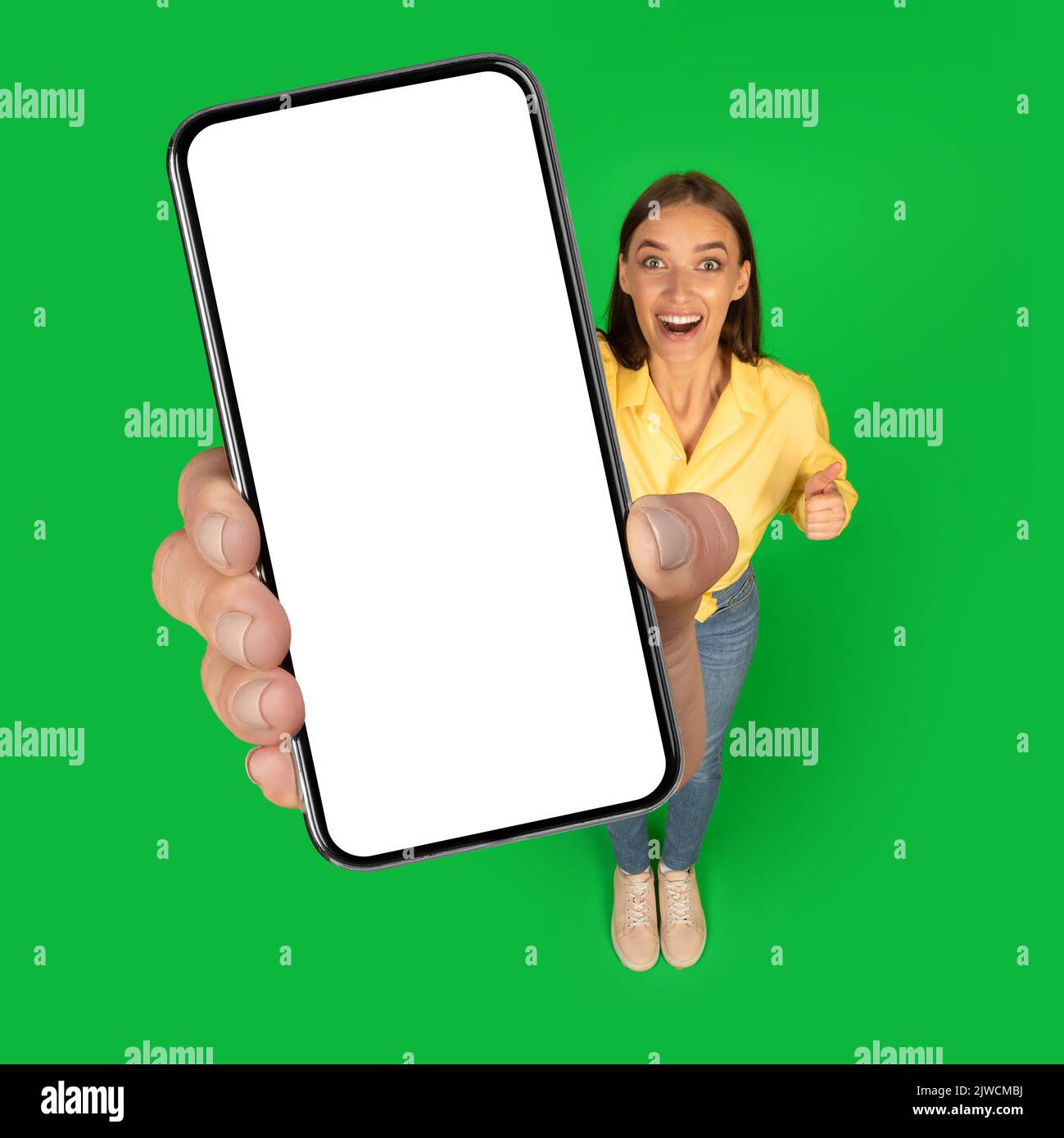 Square Shot Of Excited Lady Showing Huge Phone, Green Background Stock ...