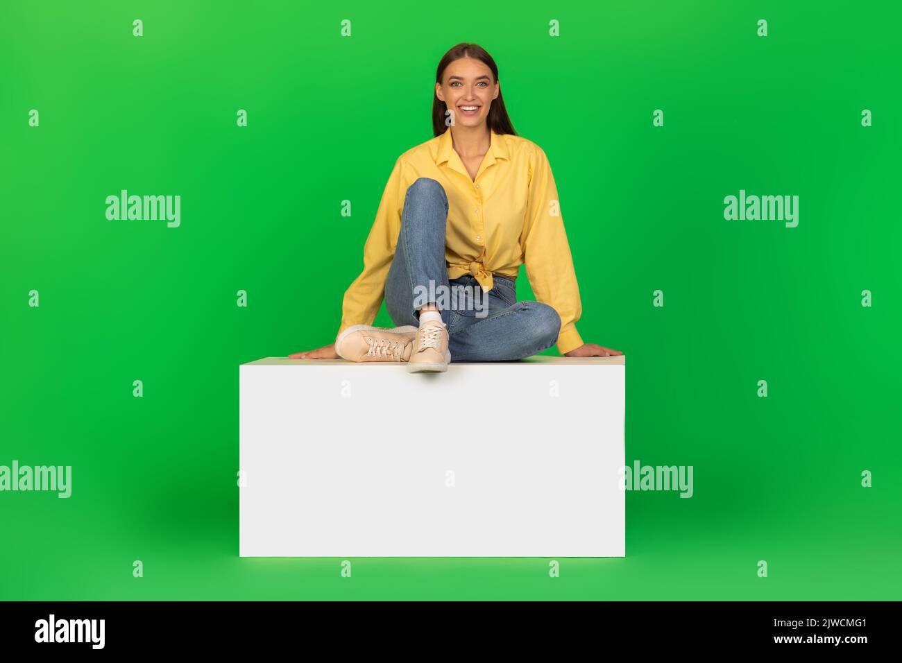 Happy Millennial Female Posing Sitting On Cube Over Green Background ...