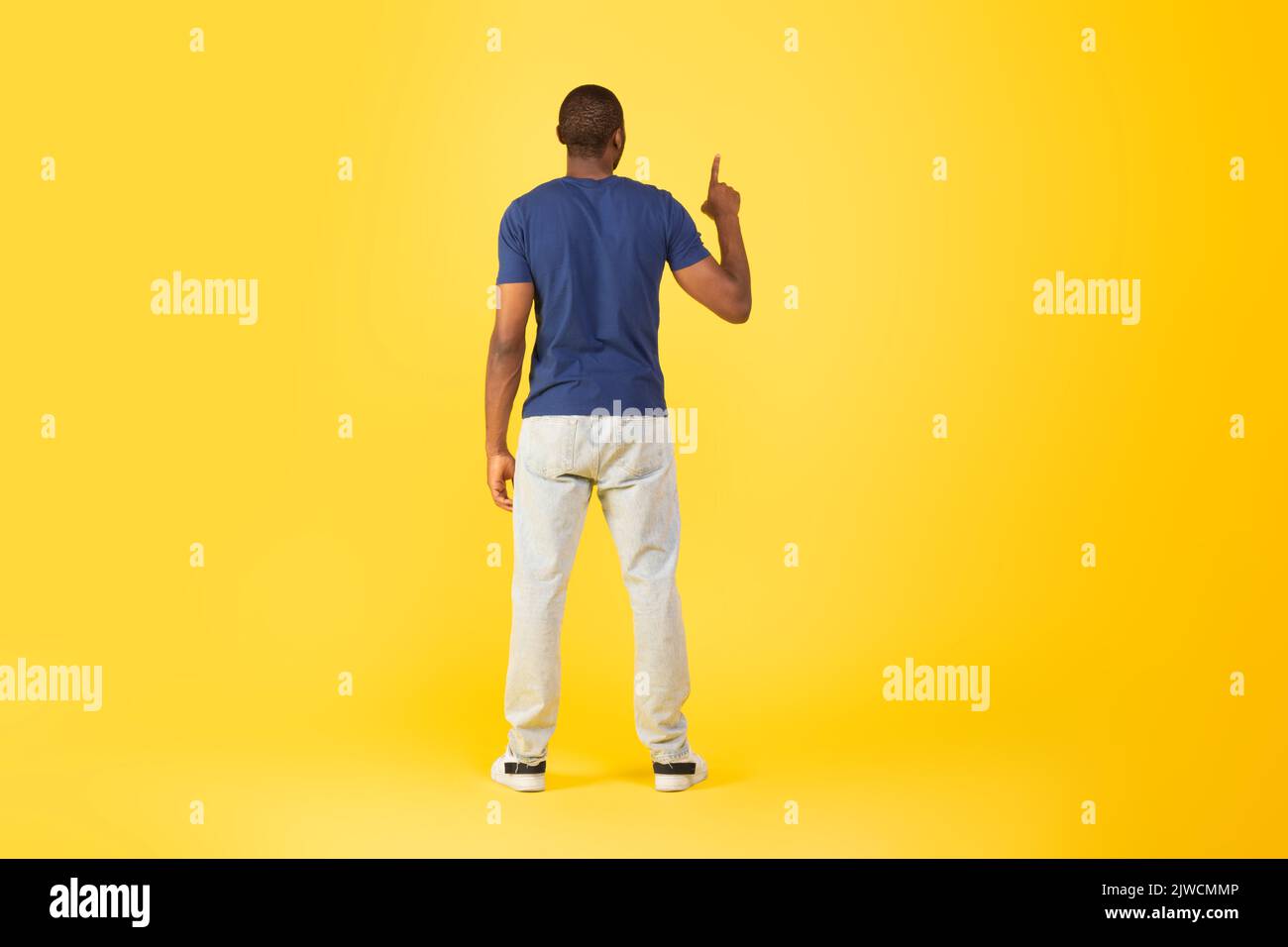 African Man Pointing Finger Up Over Yellow Background, Back View Stock ...