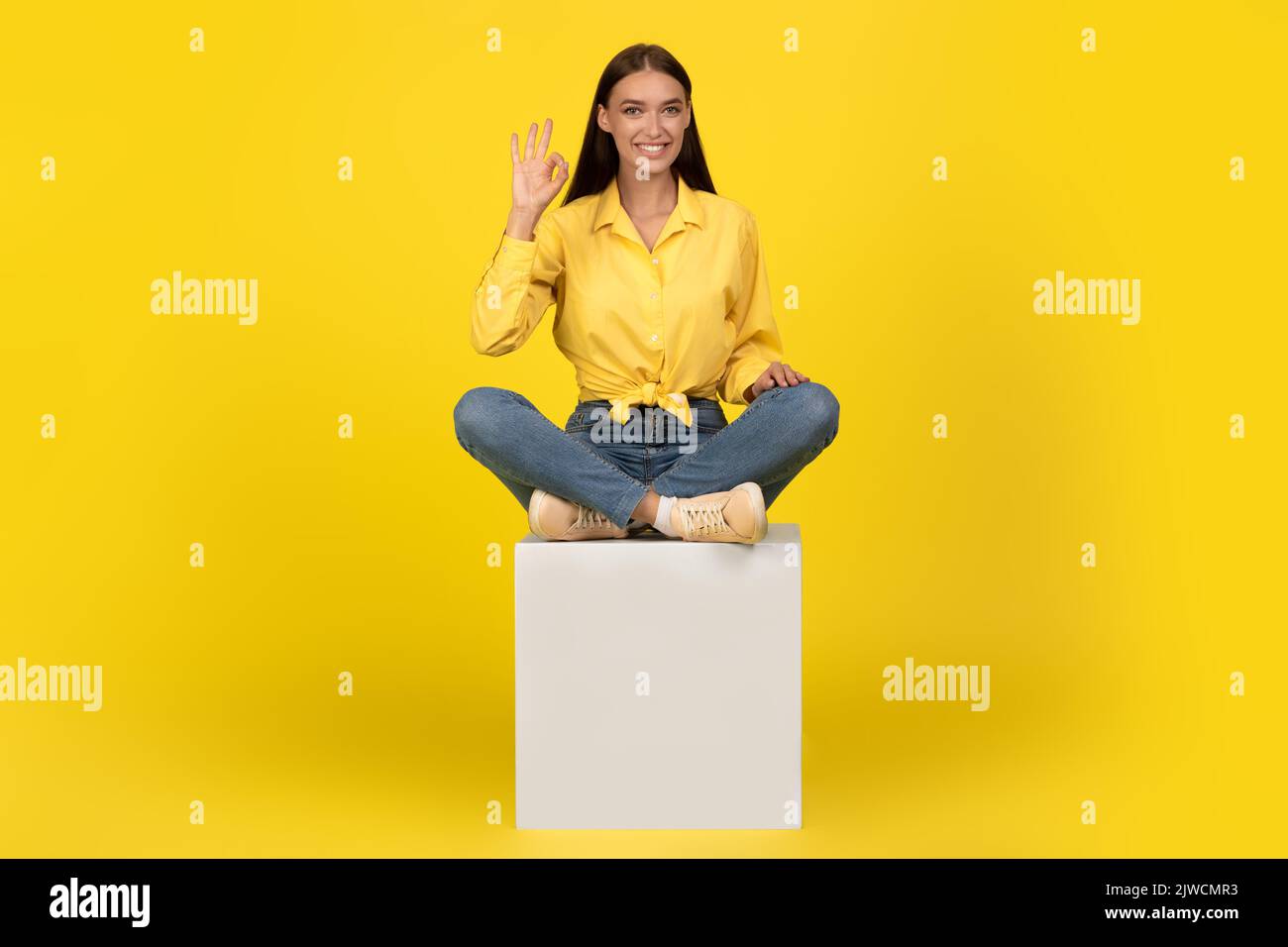 Happy Lady Gesturing Okay Sitting On Cube Over Green Background Stock ...