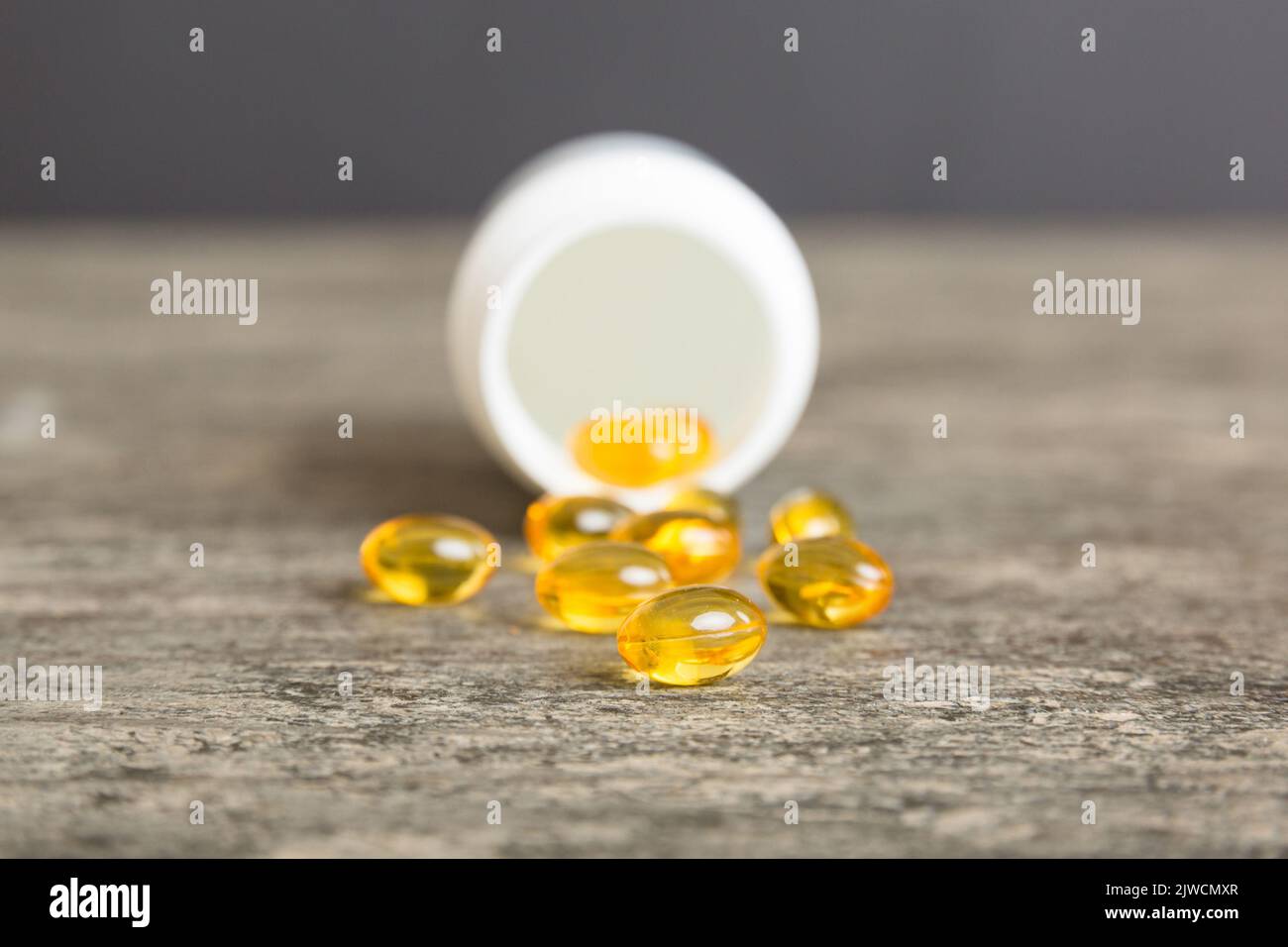 Soft gels pills with Omega-3 oil spilling out of pill bottle close-up ...